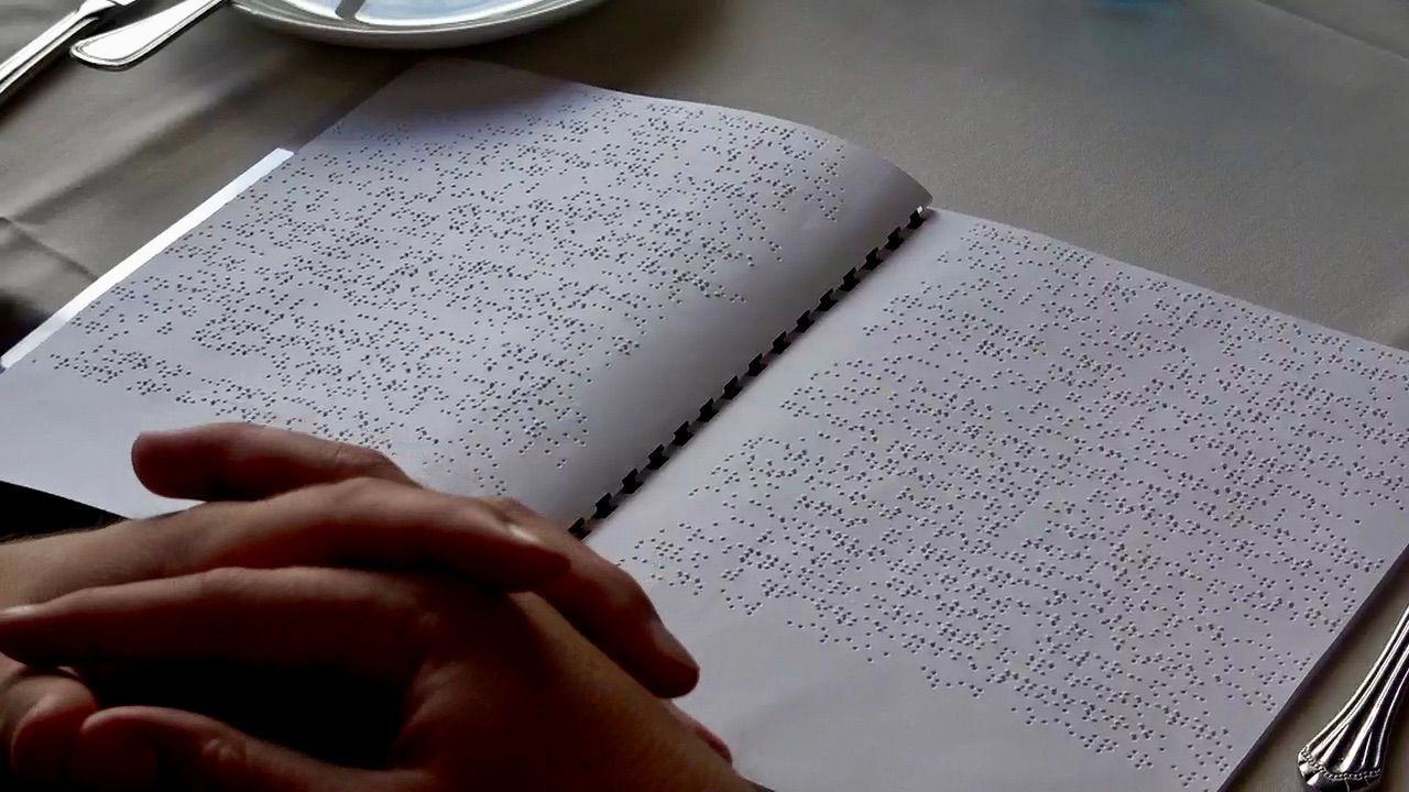 Young man in OC helps to make more menus in braille