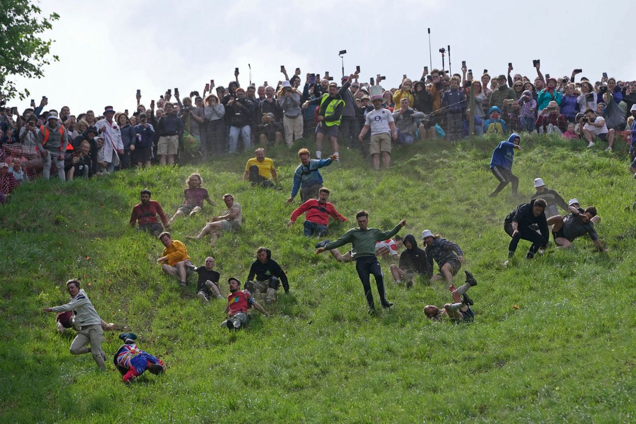 Rolling thunder: Contestants chase cheese wheel down a hill in chaotic ...