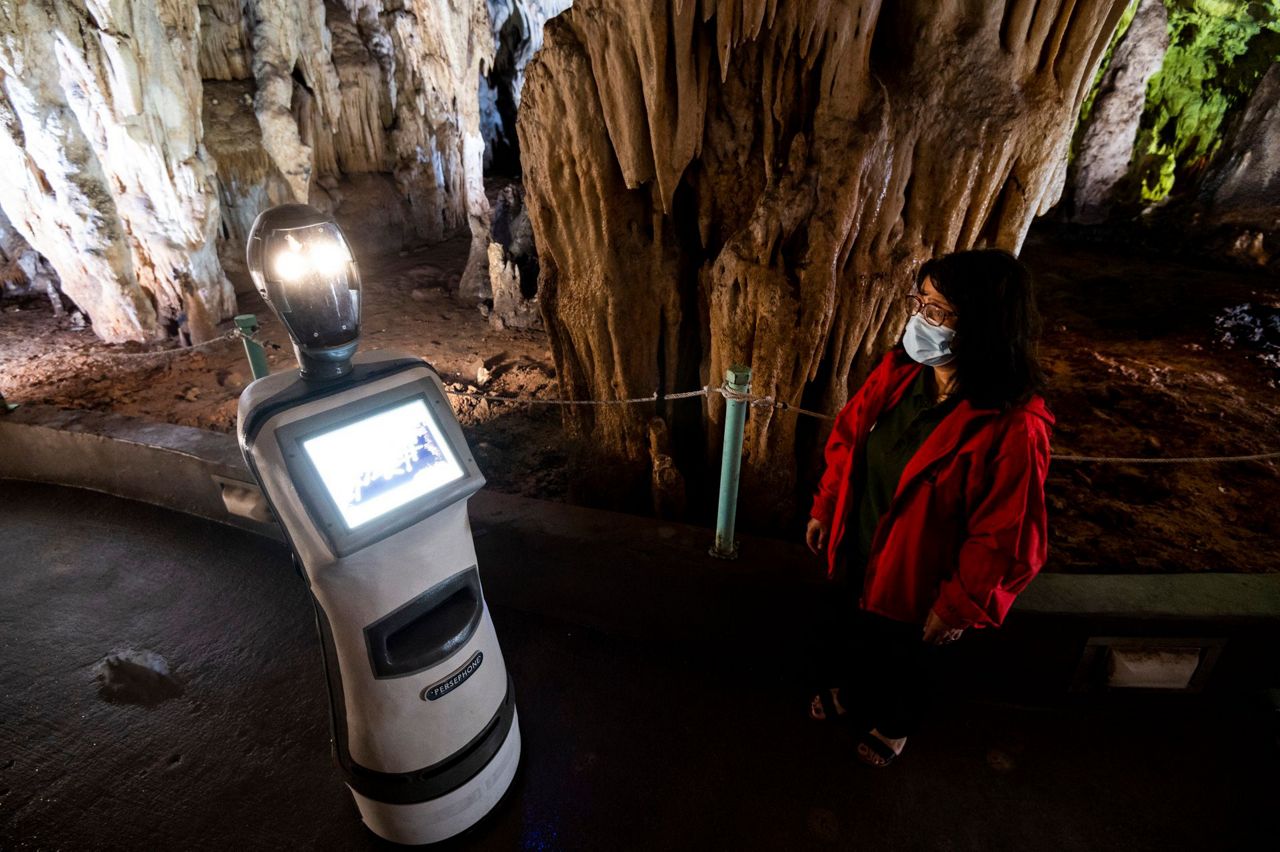 Persephone, the robot guide, leads visitors in a Greek cave