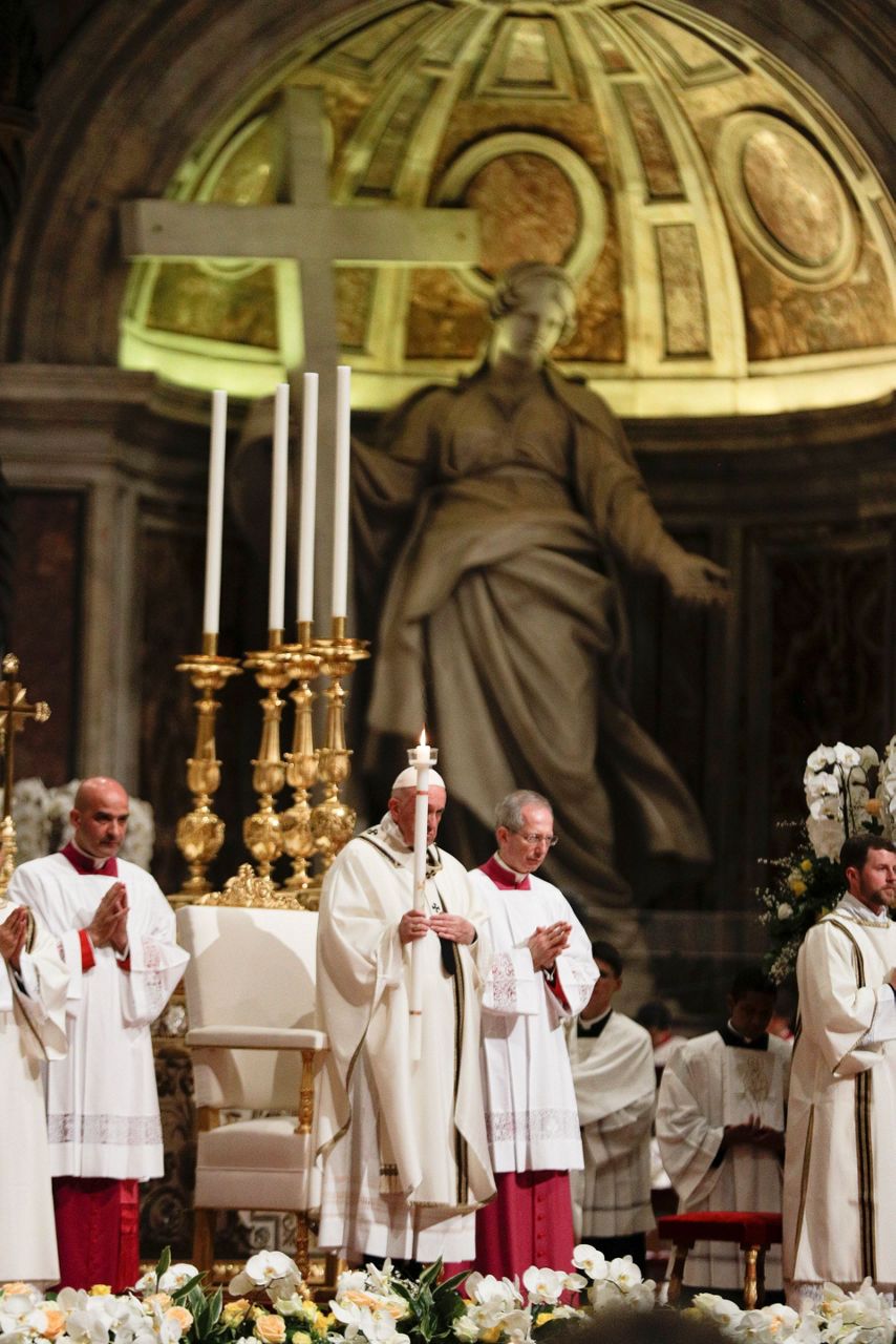 Pope carries Easter candle up aisle of darkened basilica