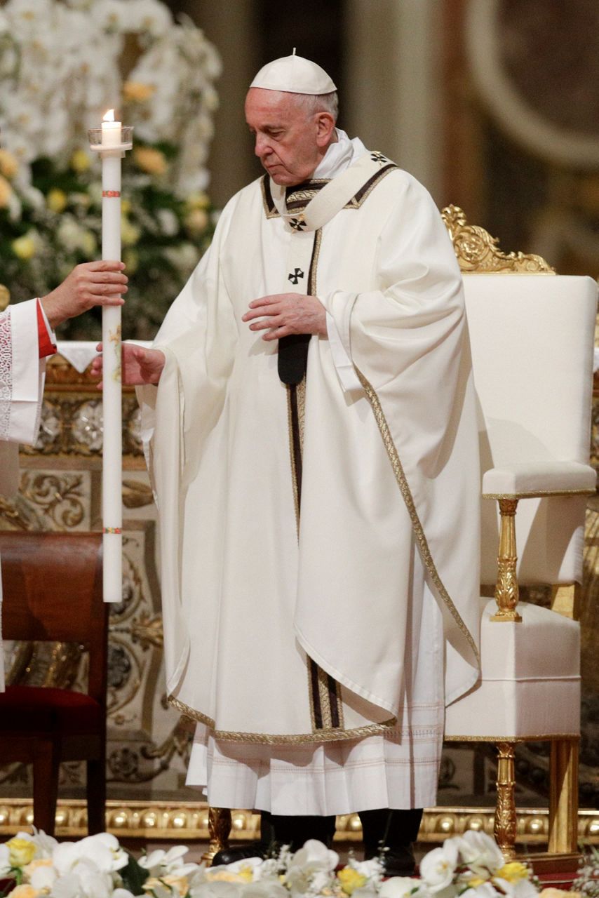 Pope carries Easter candle up aisle of darkened basilica