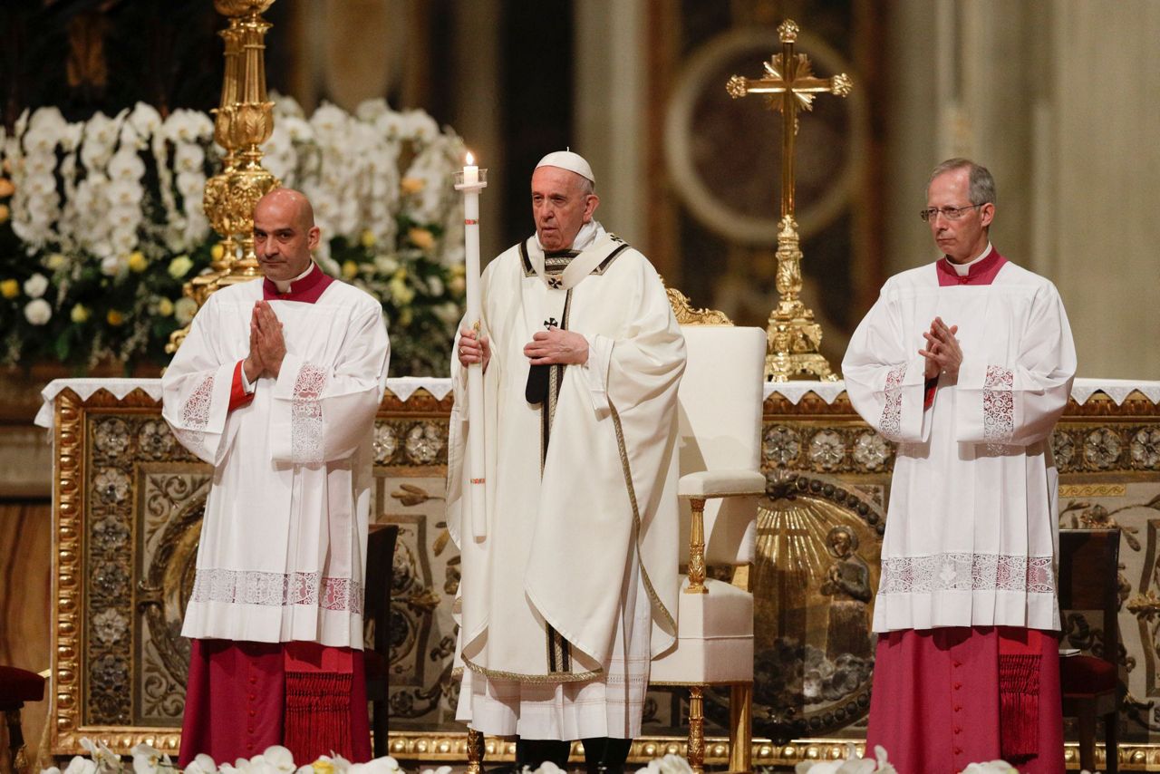 Pope carries Easter candle up aisle of darkened basilica