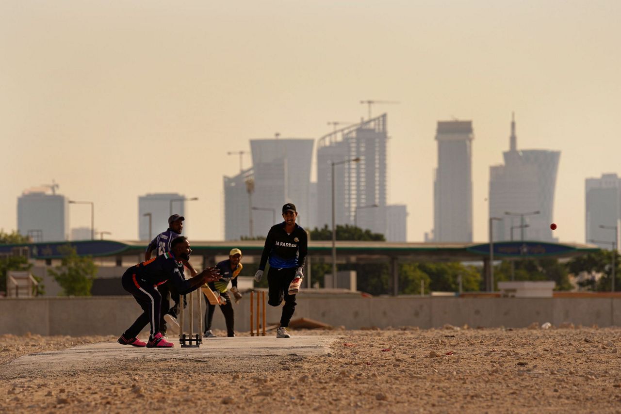 Laborers play sandlot cricket near World Cup soccer stadiums