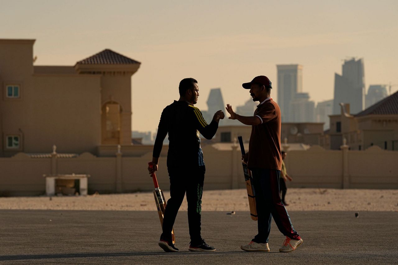 Laborers play sandlot cricket near World Cup soccer stadiums