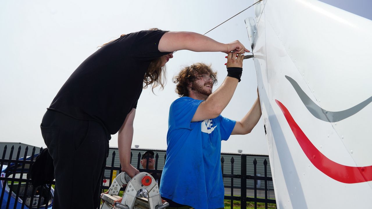 Academy at Shawnee students disassemble plane