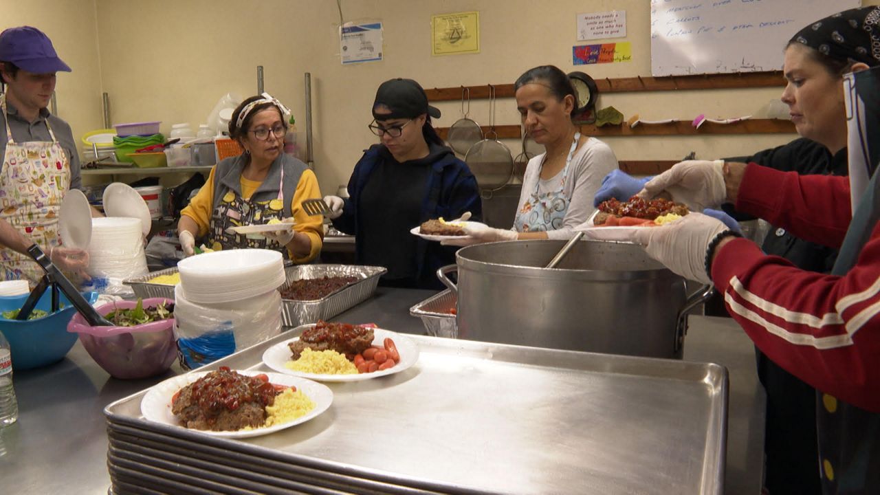 woman serves homeless in a restaurant style feeding