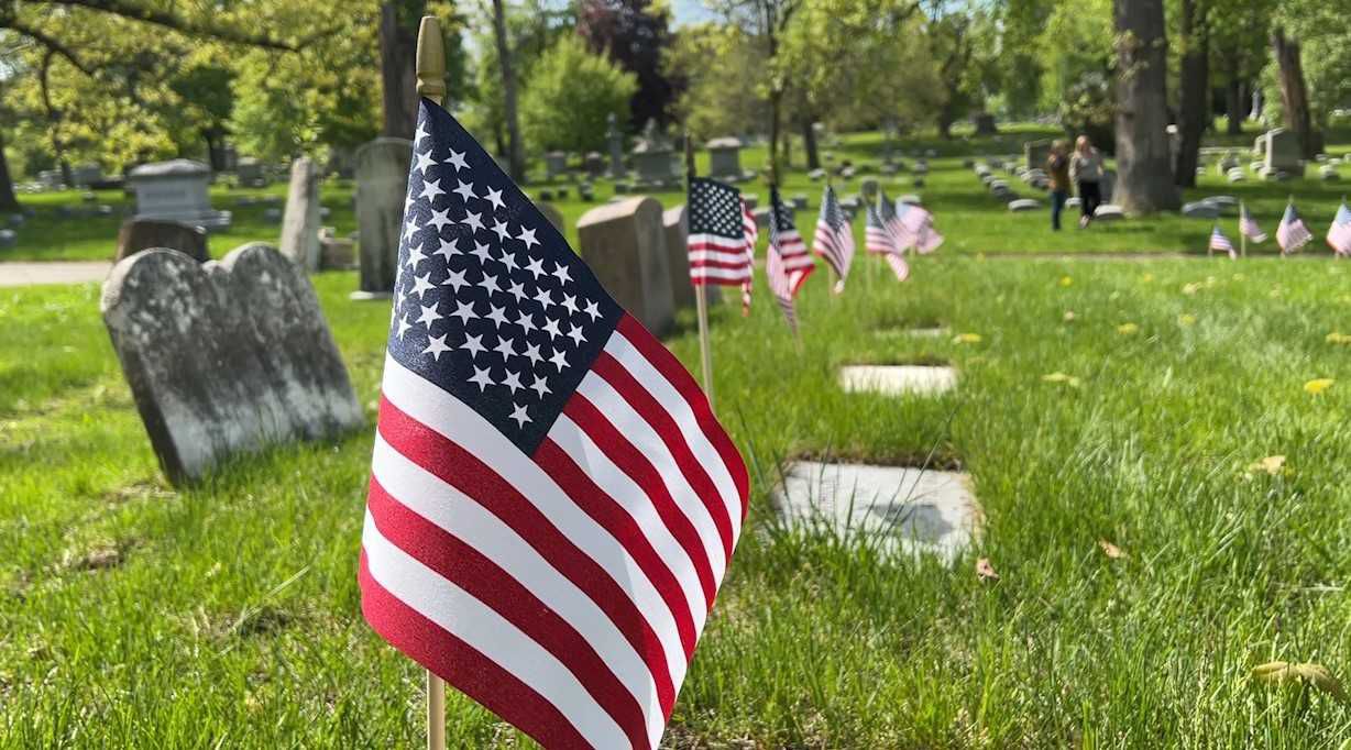 Veteran places flags on graves to honor fallen soldiers.